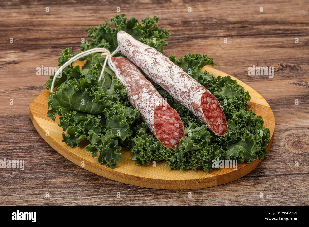 Spanish Fuet sausage with salad leaves over wooden background Stock ...