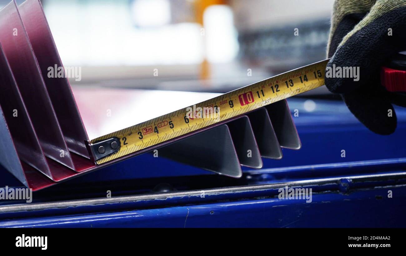 hand using a metal tape measure on sheet metal in close up selective ...