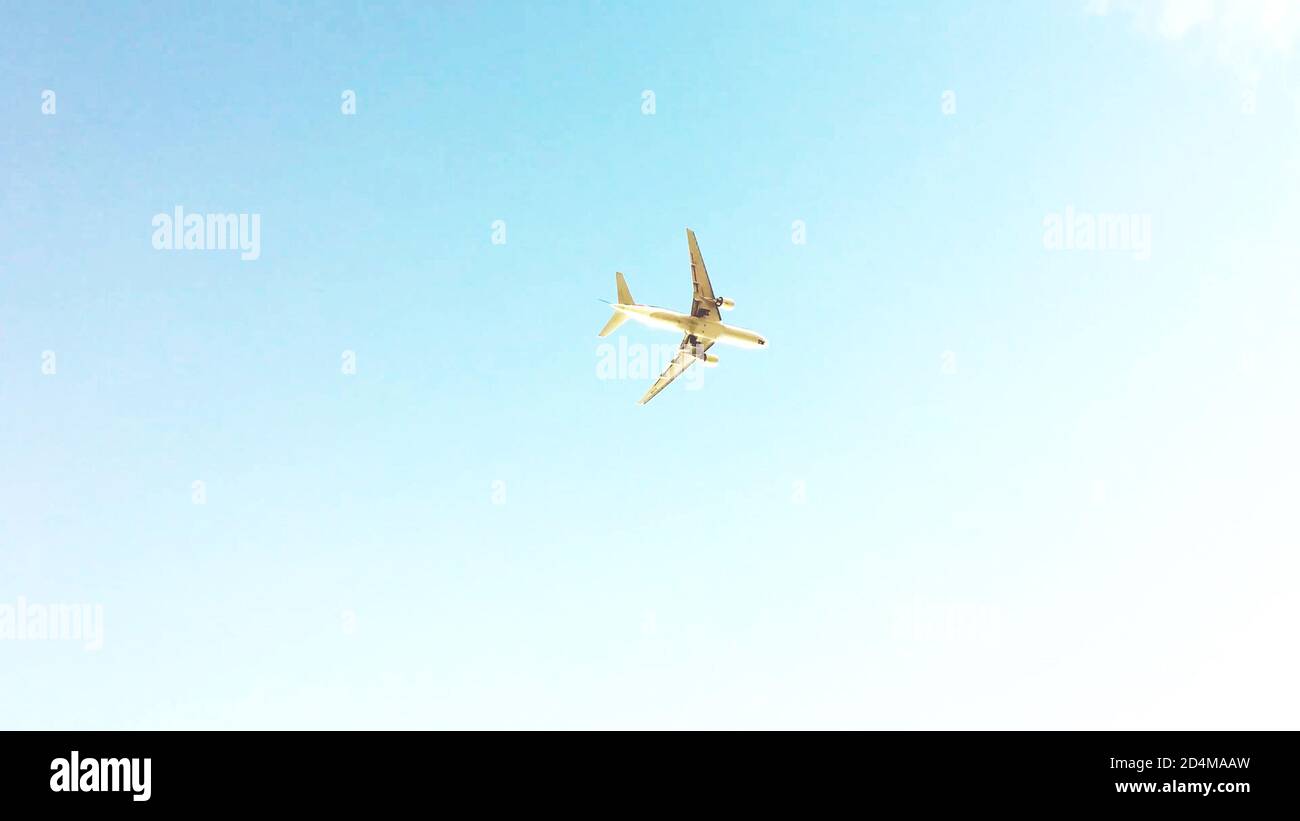 airplane in the blue clear sky, view from below of flying aeroplane ...