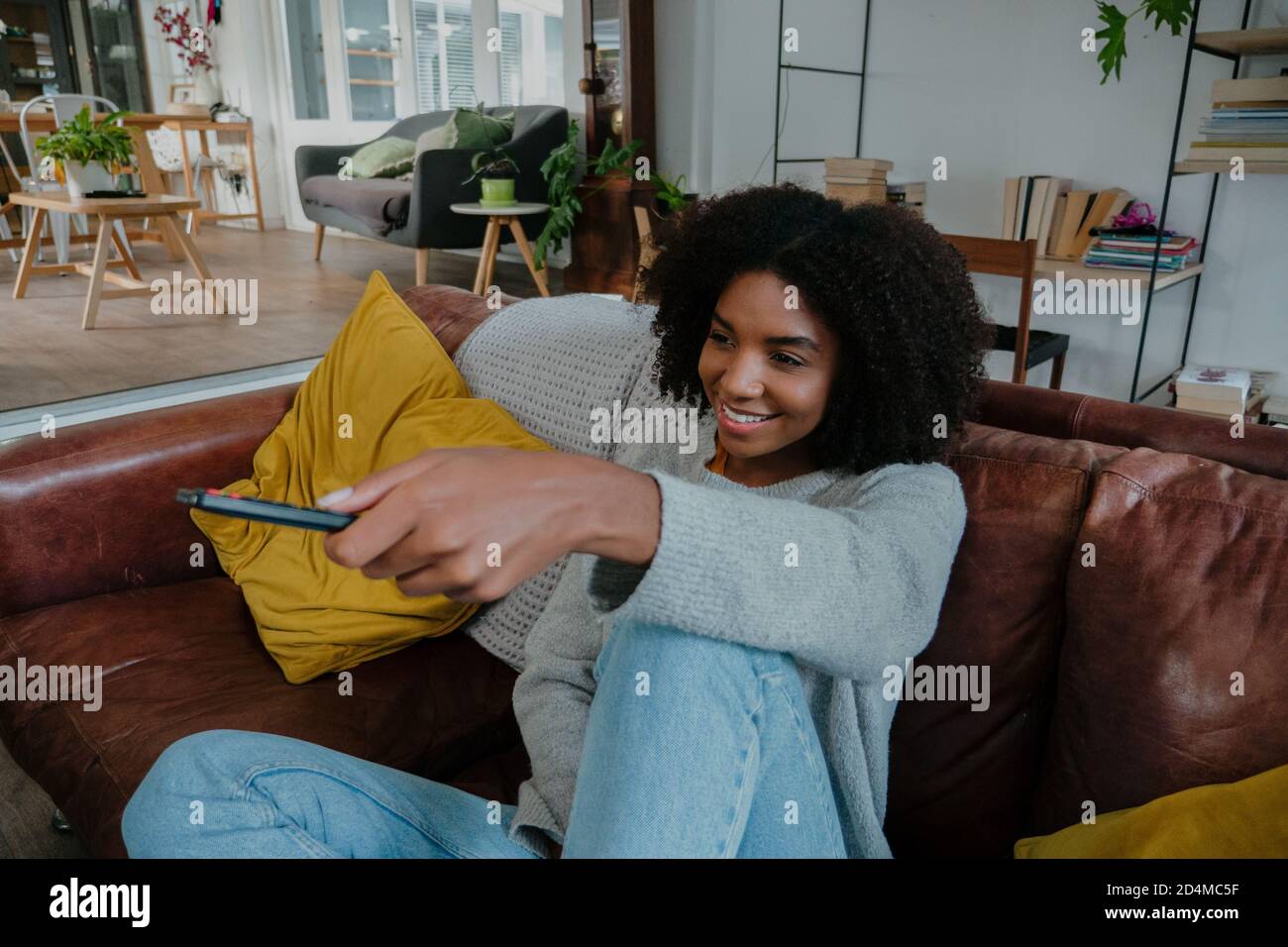 Beautiful woman scrolling on tv remote control while sitting in the ...