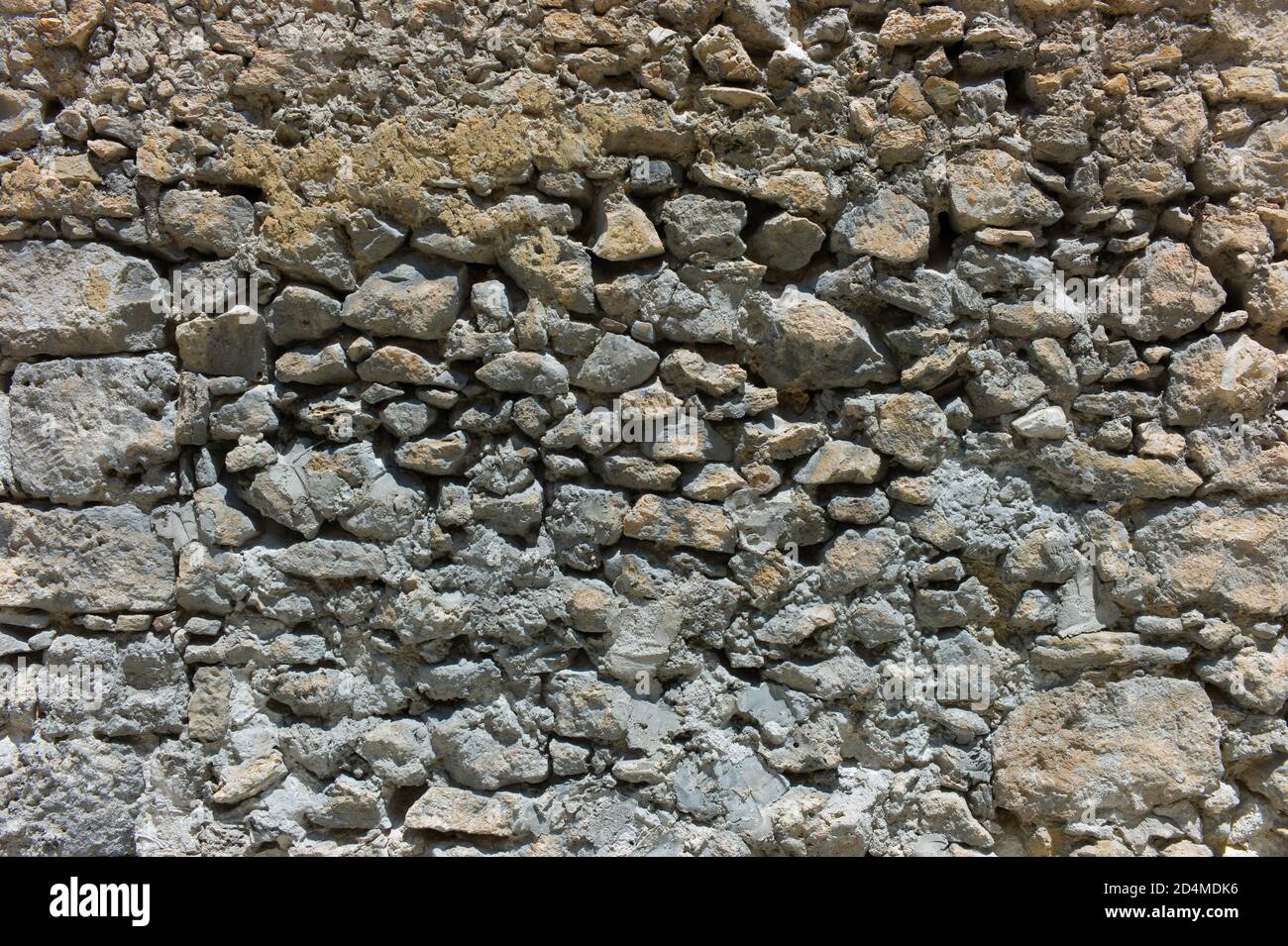 Old wall constructed from different types and sizes of stones and rocks ...