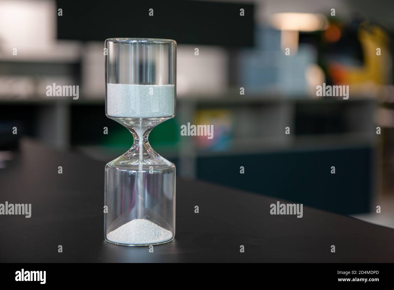 on table stand an egg timer made of glass, which is filled with small ...