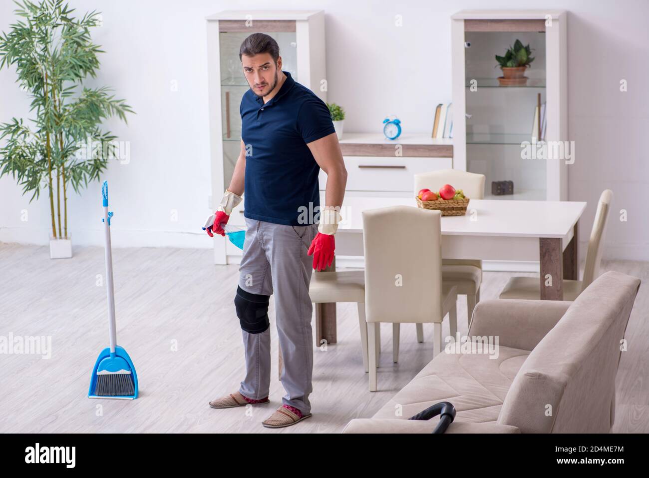 Young leg injured contractor cleaning house Stock Photo - Alamy