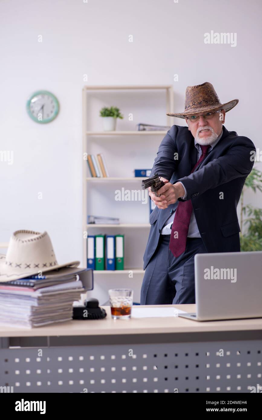 Funny old boss in cowboy hat in office Stock Photo - Alamy