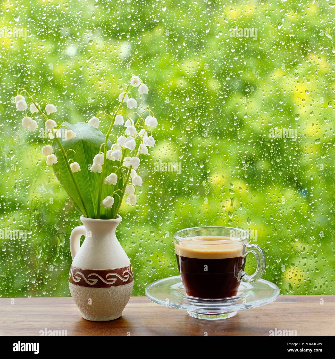 cup of coffee and lilies of the valley on the window. Rain drops on the ...