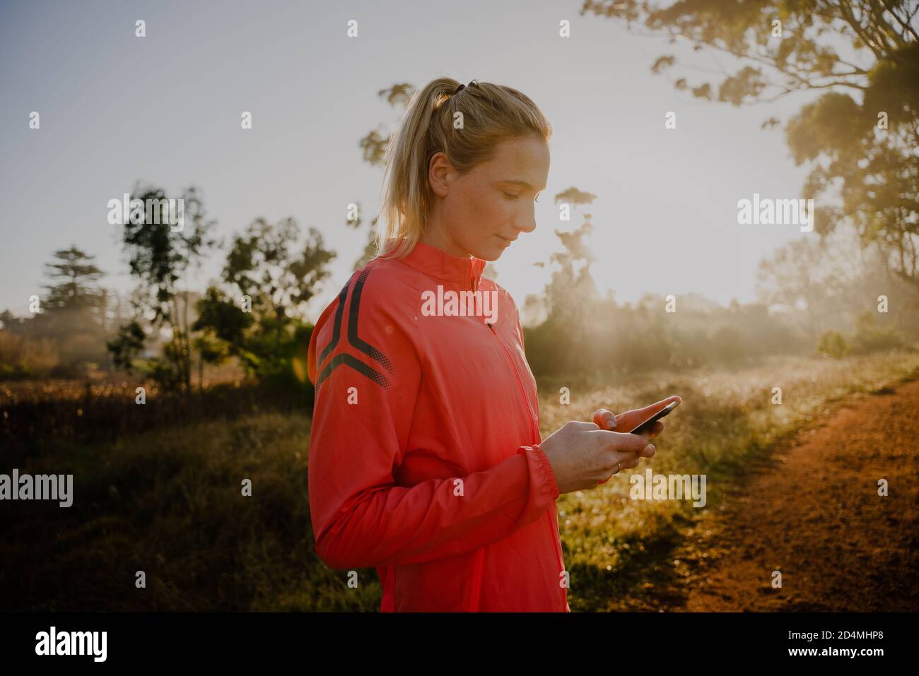 Female athlete texting on smartphone while on an outdoor run in forest ...