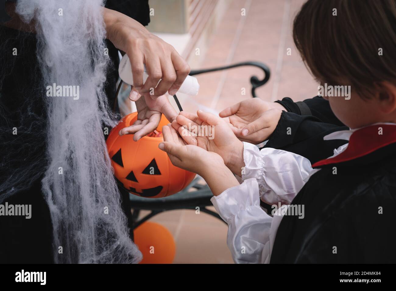 An adult disinfects children's hands before giving them candy on ...