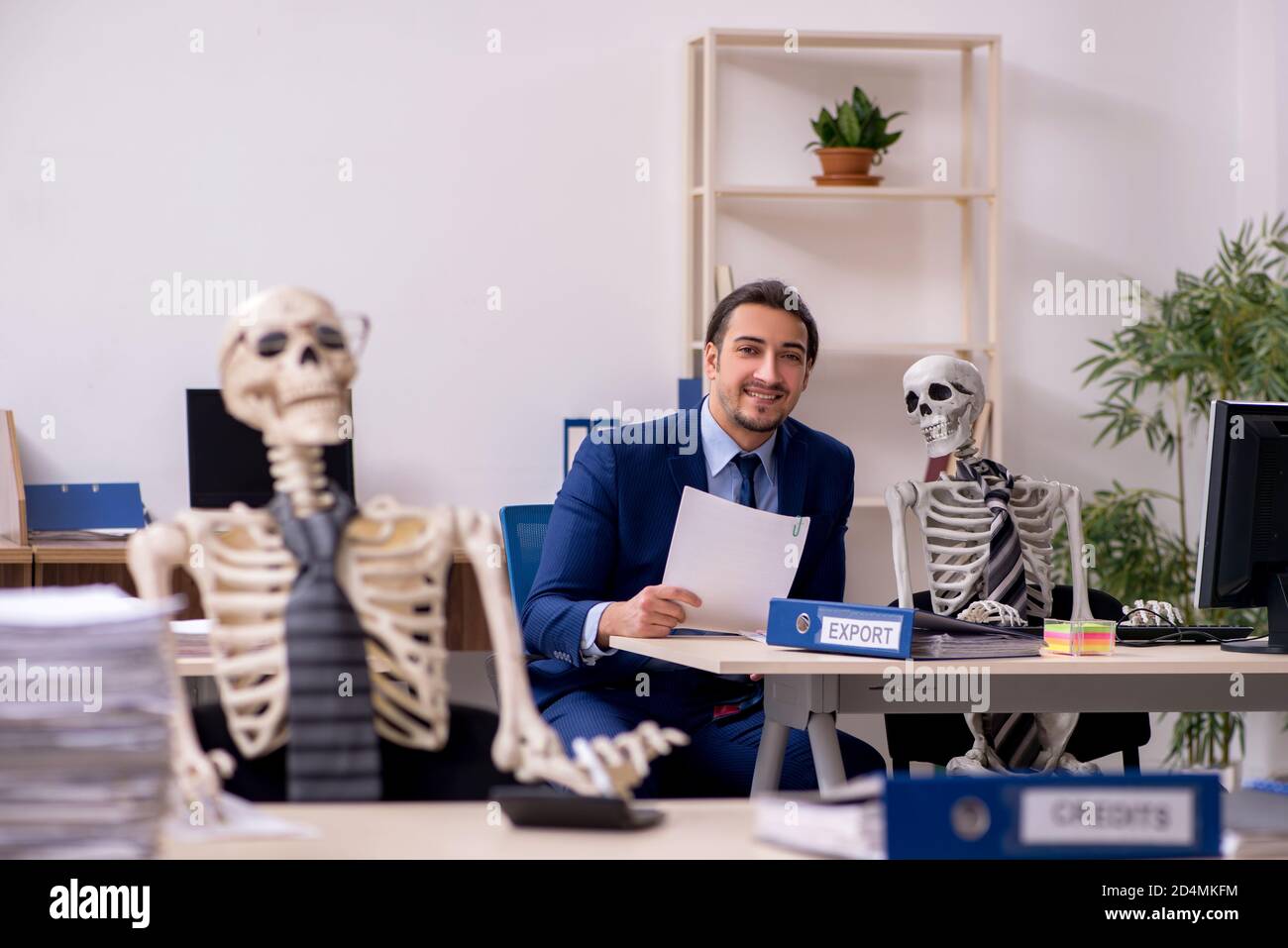 Young employee with skeletons in the office Stock Photo - Alamy