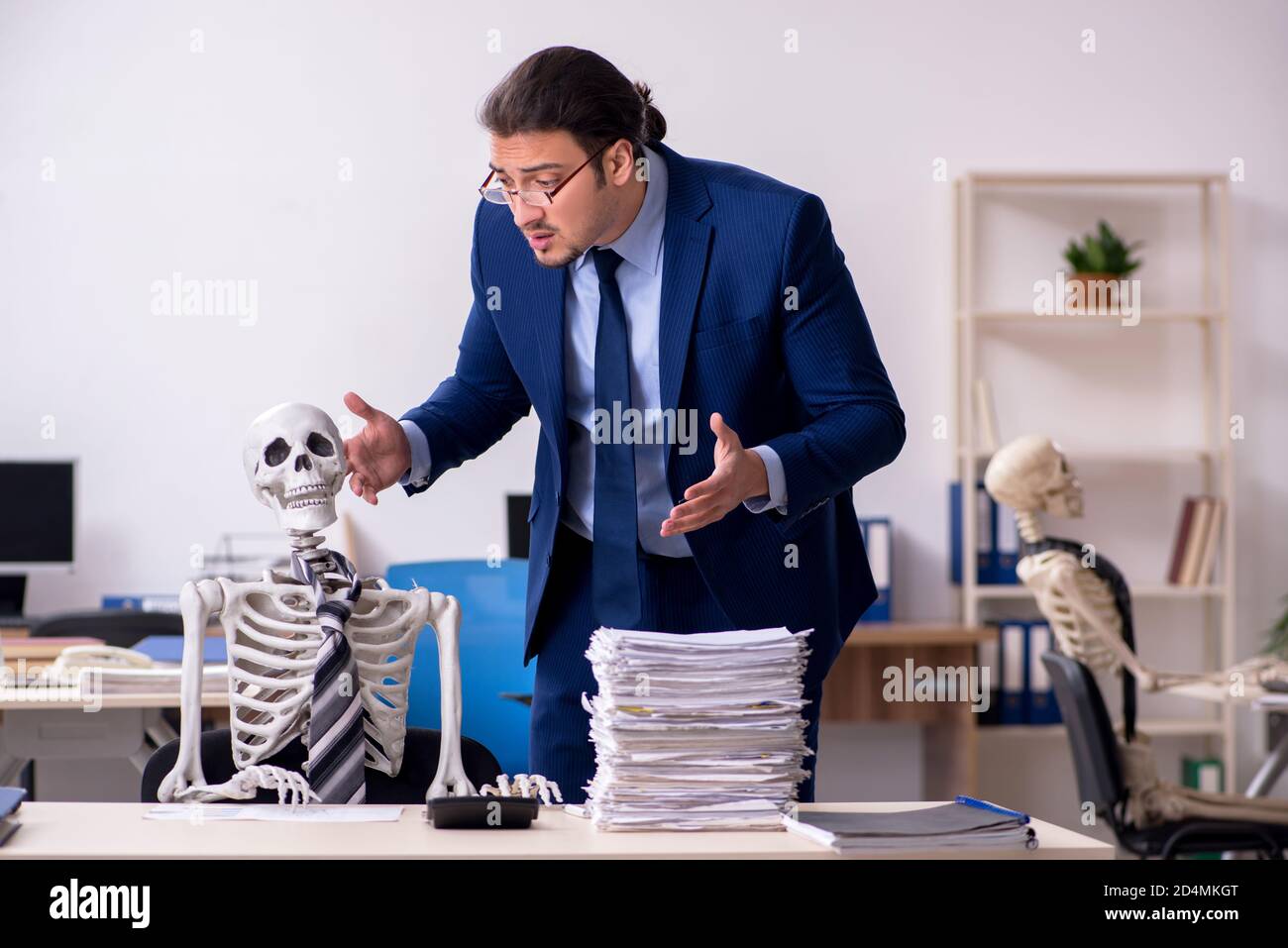Young employee with skeletons in the office Stock Photo - Alamy