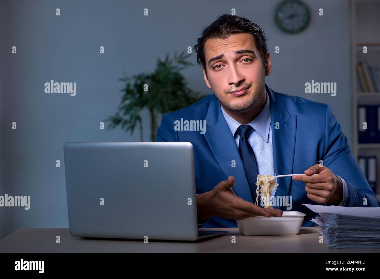 Hungry employee working late in office Stock Photo - Alamy
