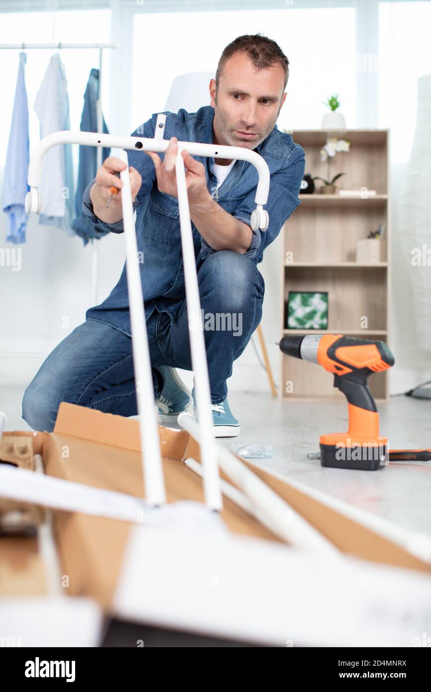 man putting together self assembly furniture in new home Stock Photo ...