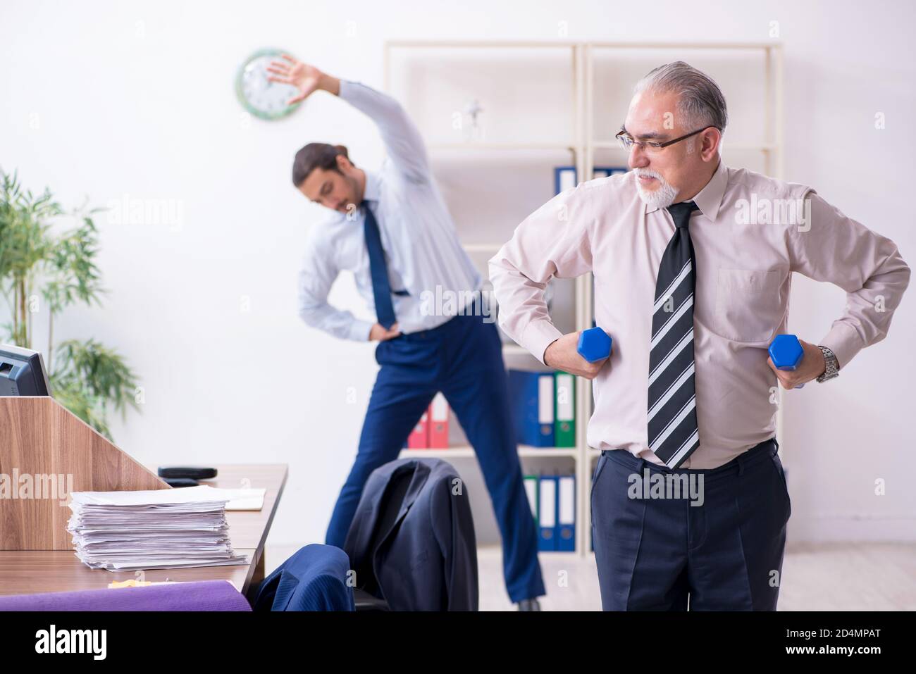 Two employees doing physical exercises at the workplace Stock Photo - Alamy