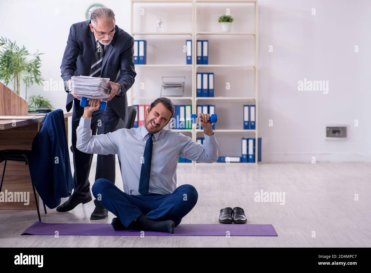 Two employees doing physical exercises at the workplace Stock Photo - Alamy
