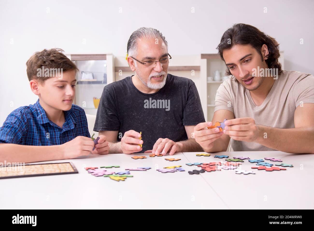 Three generations of family playing jigsaw puzzle Stock Photo - Alamy