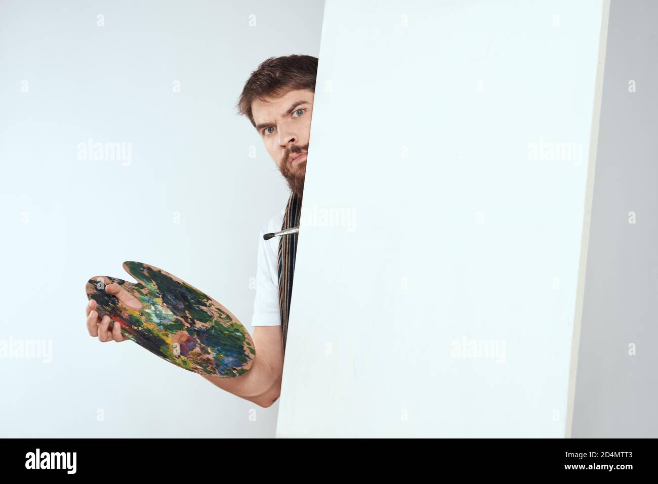 Male artist hiding behind an easel palette drawing art Stock Photo - Alamy