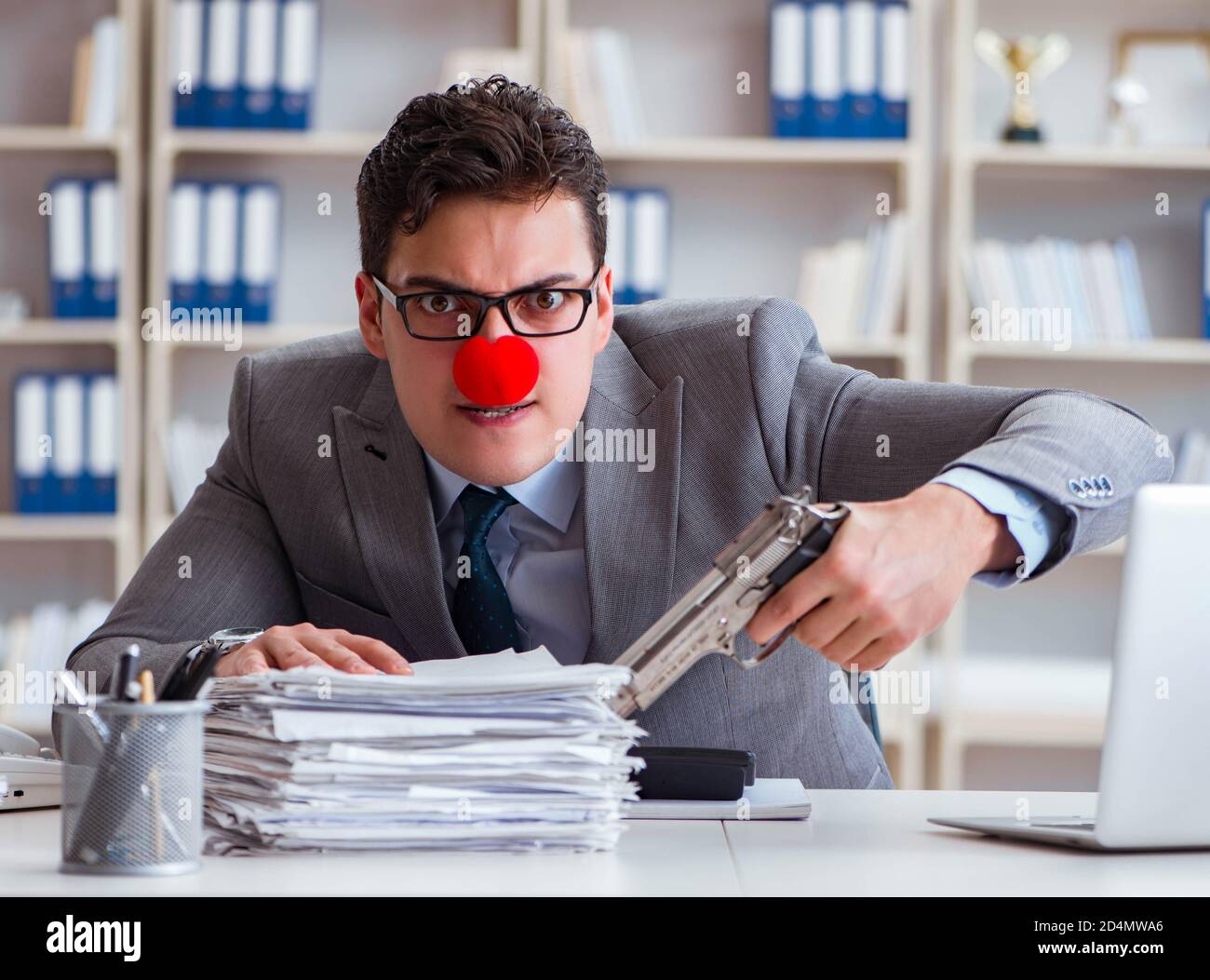 Clown businessman working in the office angry frustrated with a gun ...