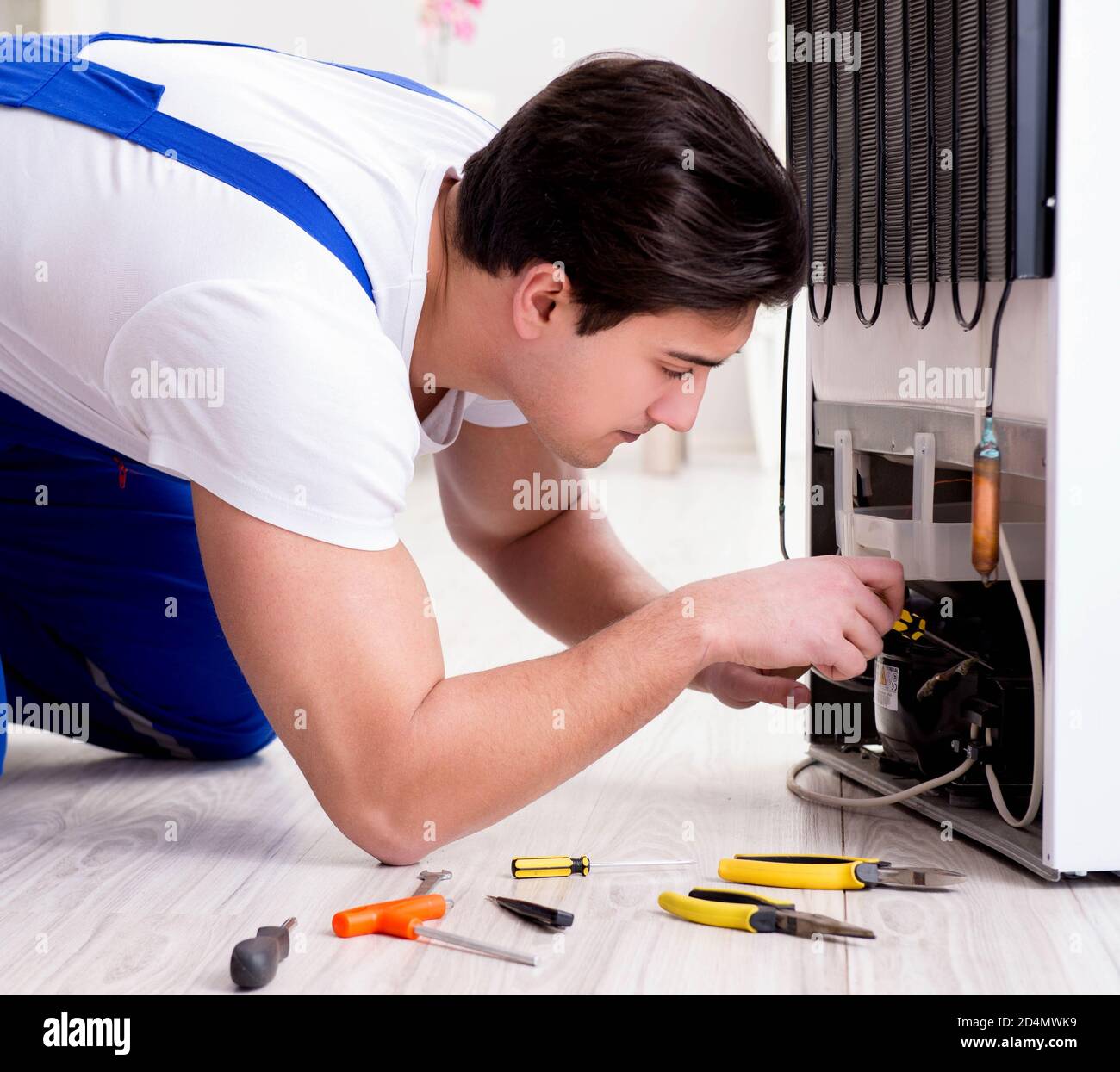 The repairman contractor repairing fridge in diy concept Stock Photo ...