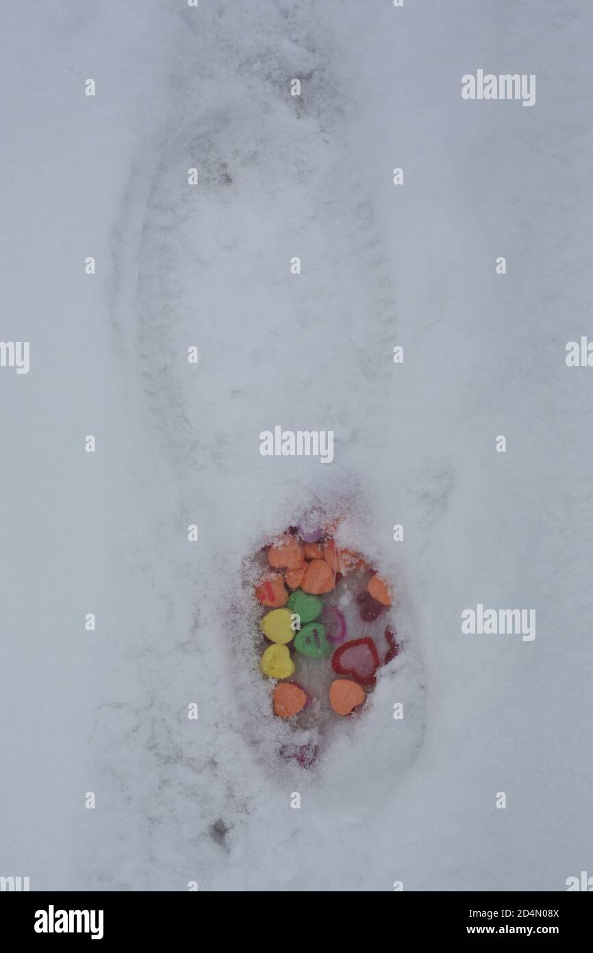 A footprint on snow reveals buried Valentine candy hearts Stock Photo ...