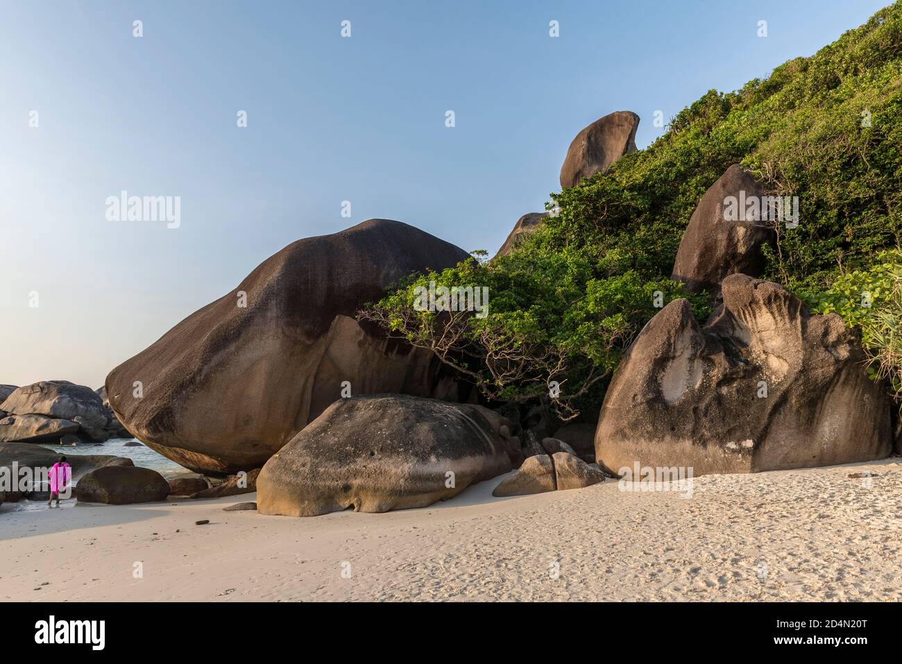 Huge coastal boulders and rocks, and a small figure of a girl in a ...