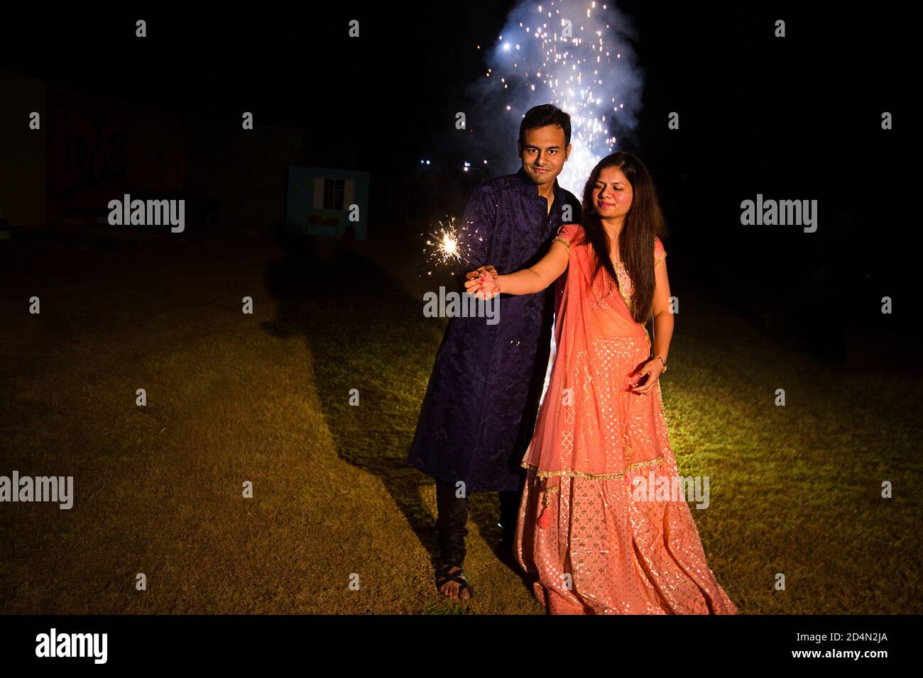 Young Indian couple in traditional wear celebrating holding sparklers ...