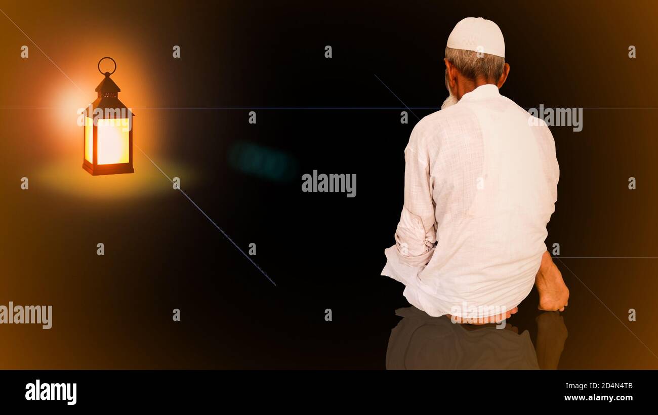 A man is offering Namaz in the light of a lamp at night. isolated on ...