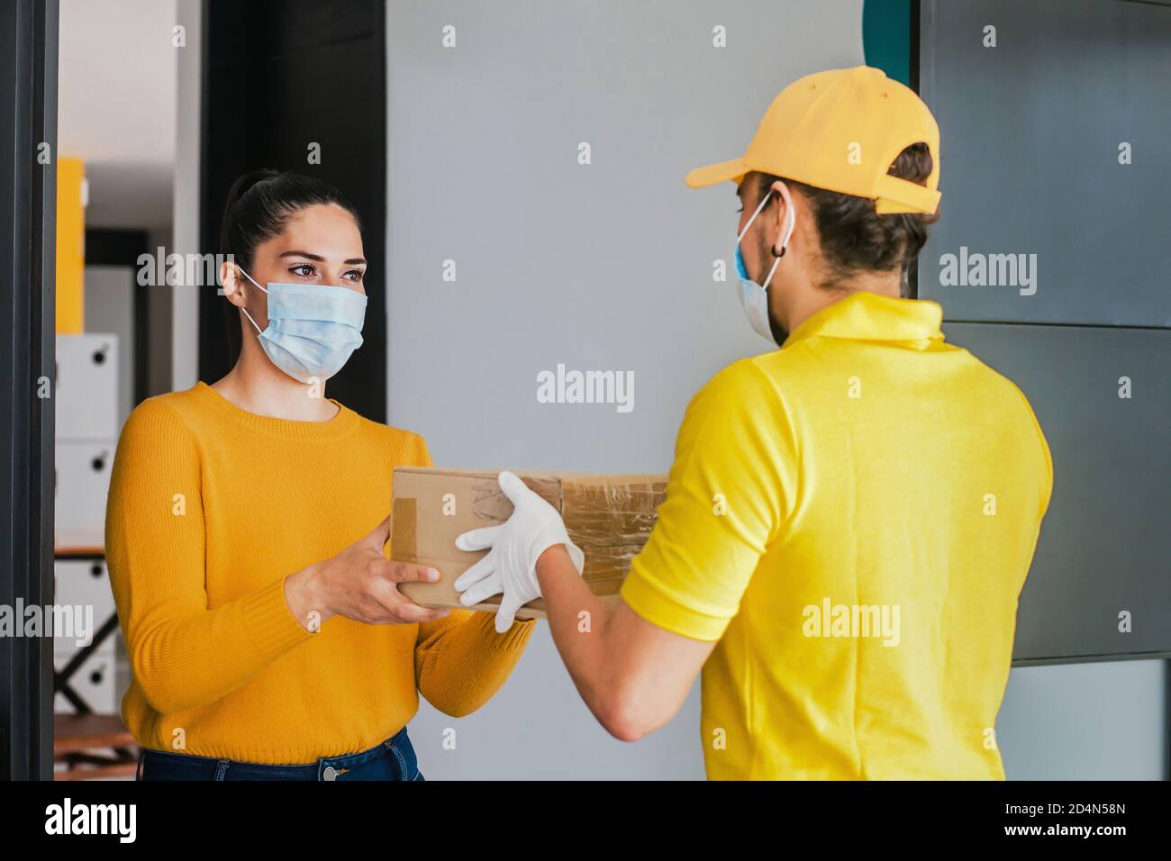 Latin delivery man with mask holding and carrying a cardbox in ...