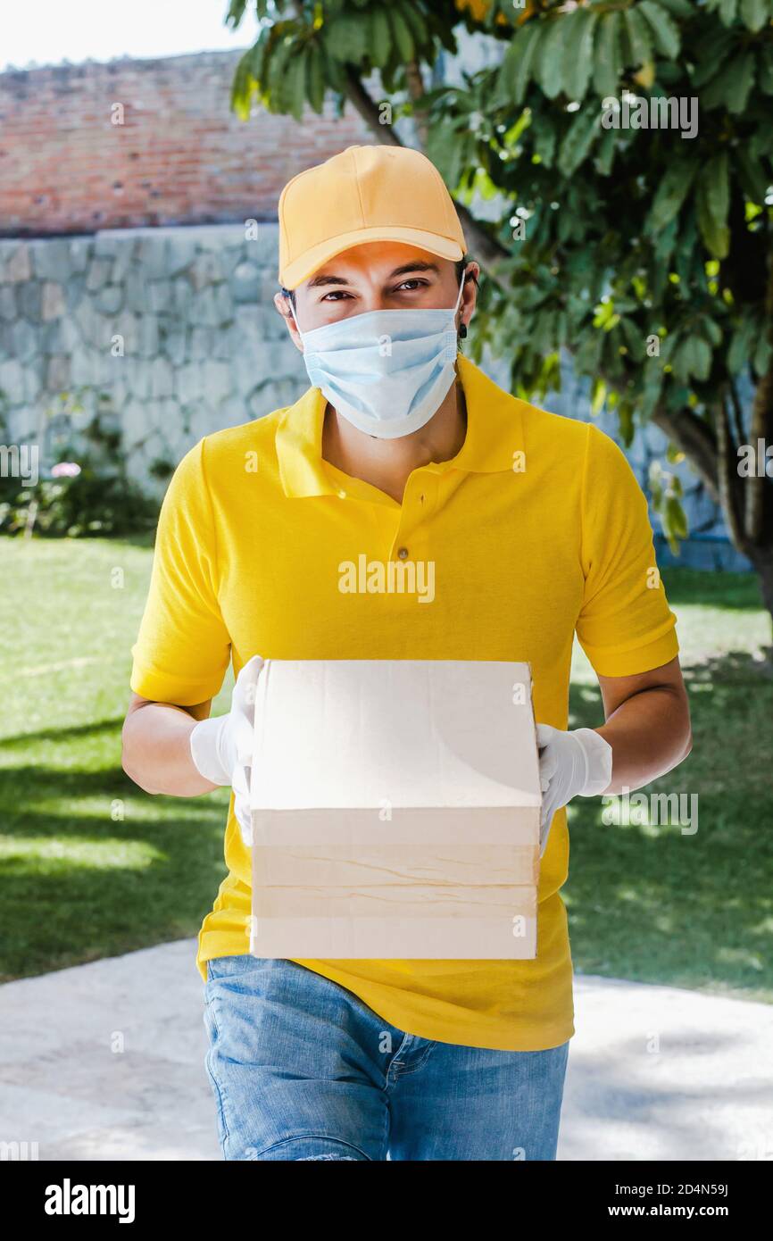 Latin delivery man with mask holding and carrying a cardbox in ...