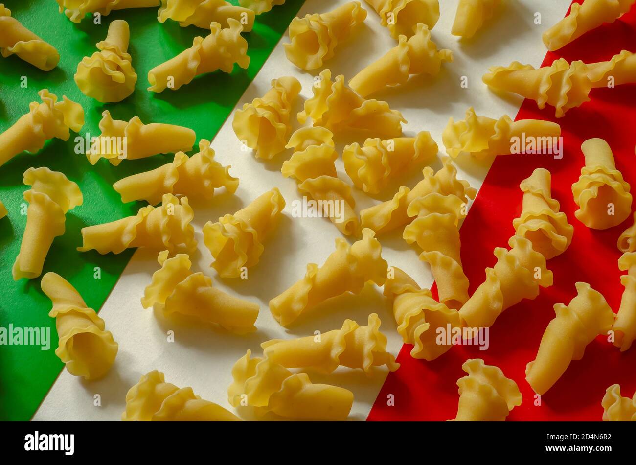 Dry gigli pasta on a green-white-red background. A serving of uncooked ...