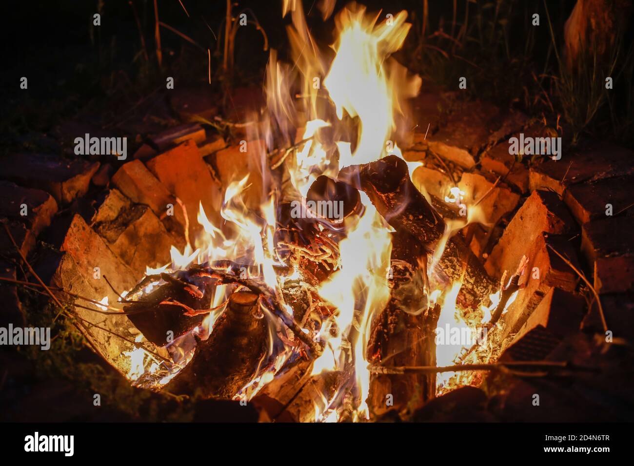 Details of a wood fire in a red brick fireplace dug in the ground Stock ...