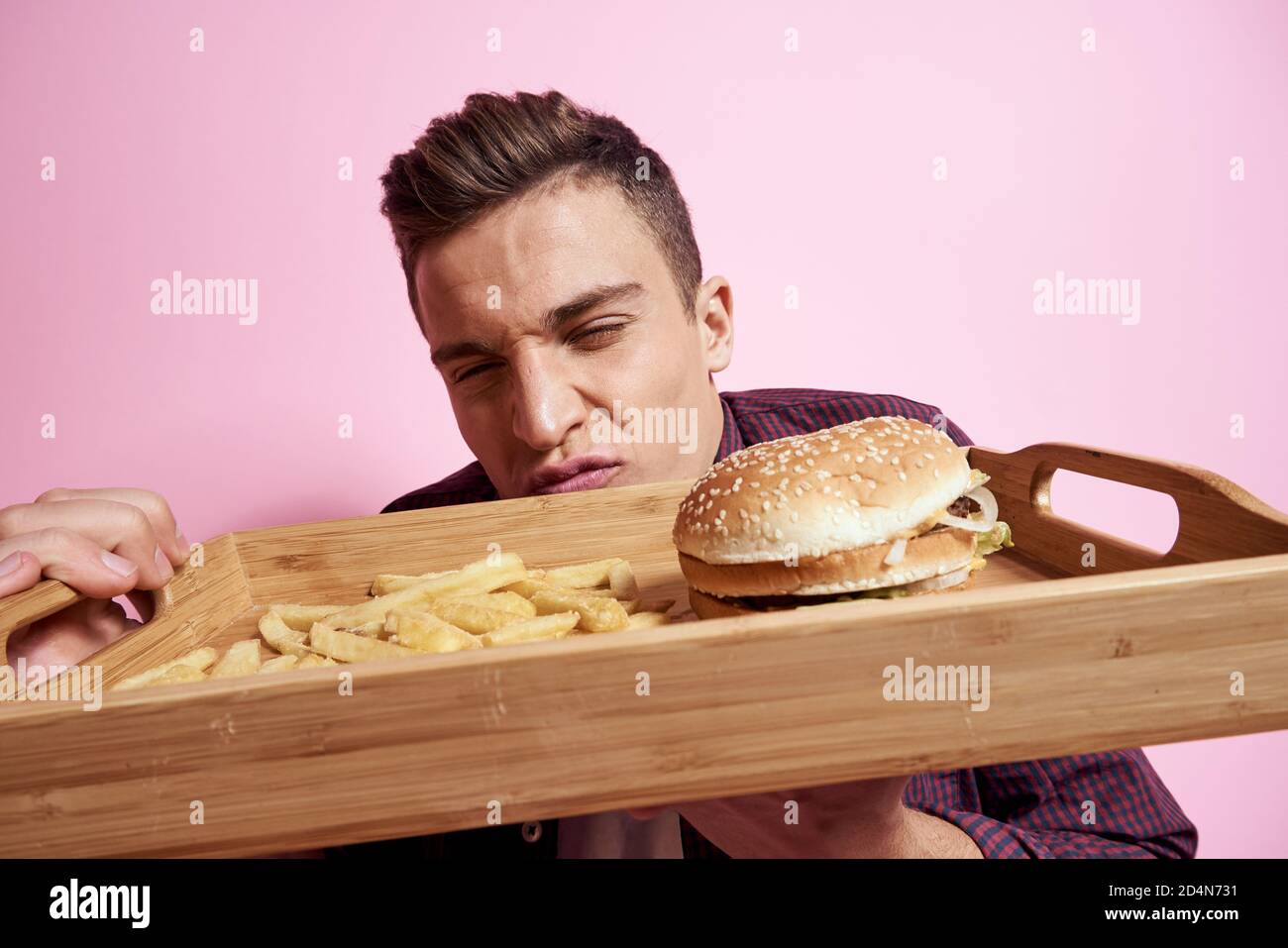 Man with fast food eating hamburger french fries pink background Stock ...