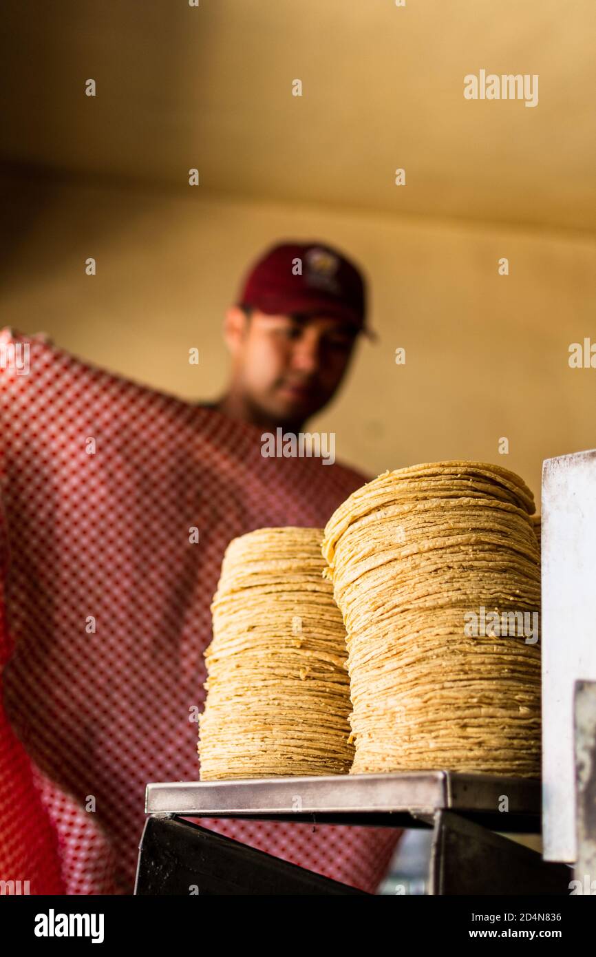 Vertical shot of a Mexican male preparing tortilla bread in his shop ...