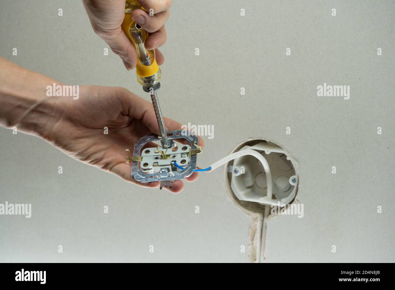 A man installs an electrical outlet in the wall. Installation wire into ...