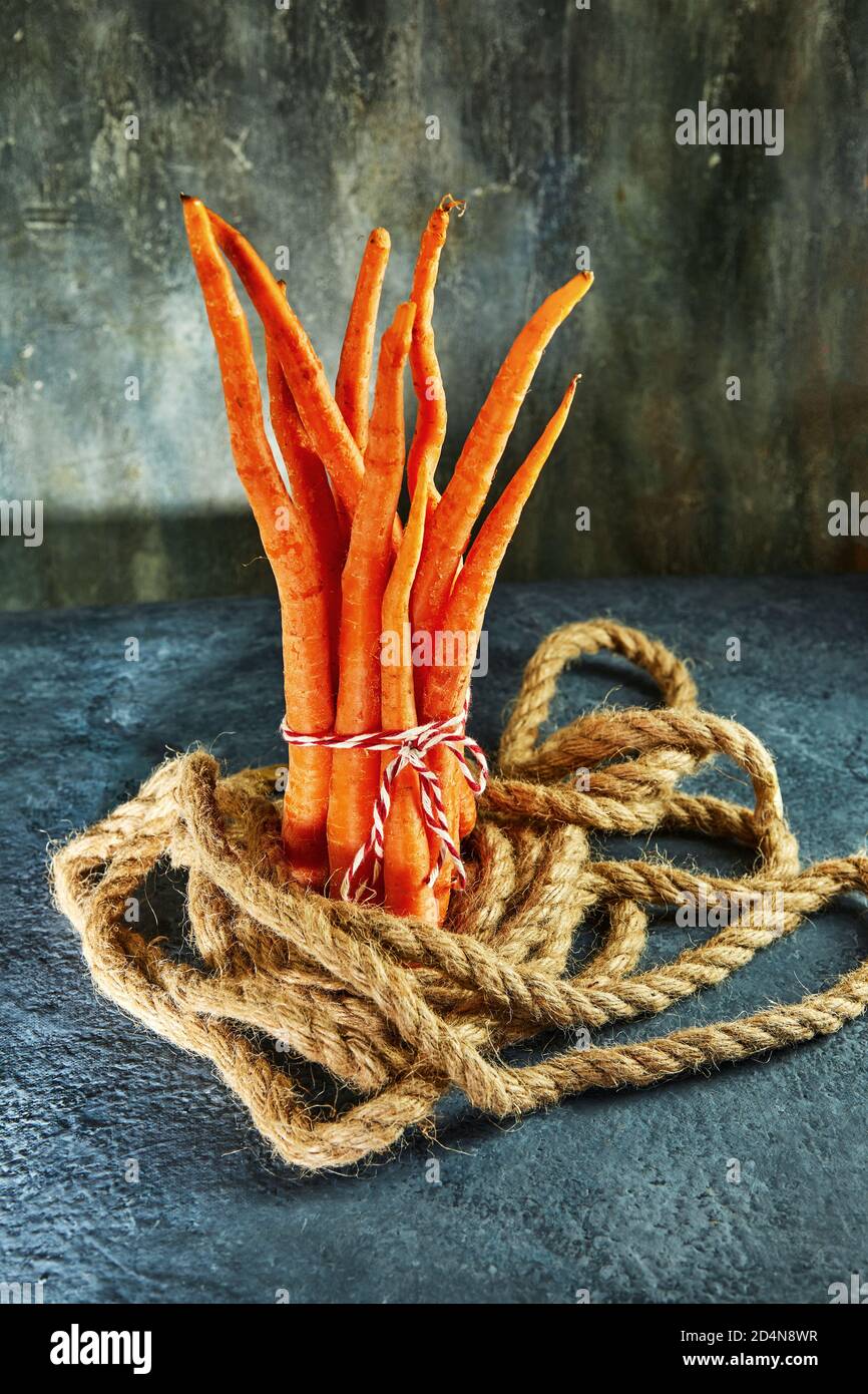 Ugly food. Deformed organic carrots on a rope on a blue background ...