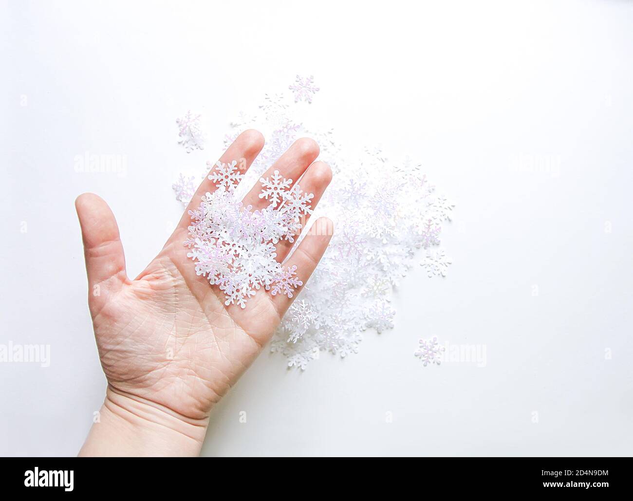 White artificial snowflakes in a woman's hand on soft light background ...
