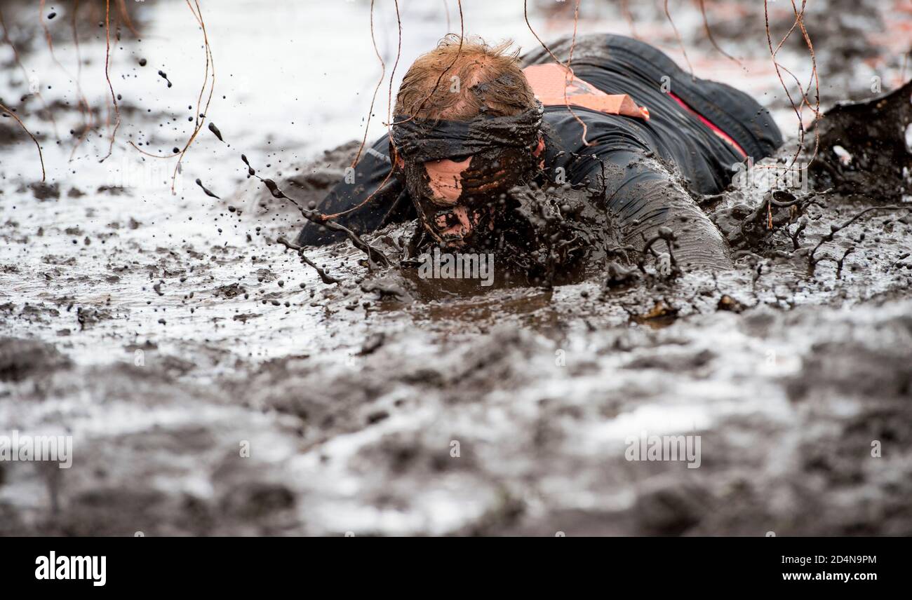 Mud race runners. Crawling,passing under a barbed wire obstacles during ...