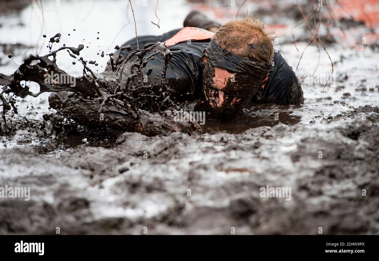 Mud race runner, man running in mud. Runners during extreme obstacle ...