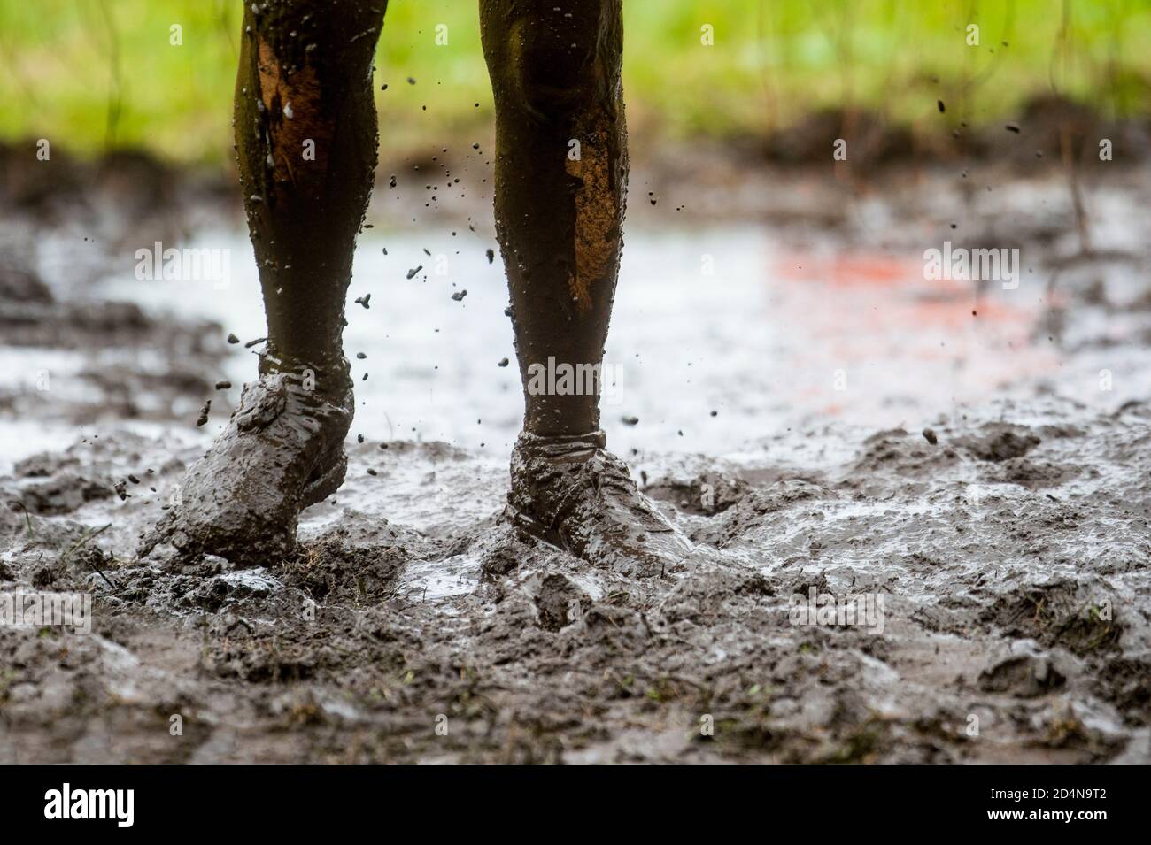 Mud race runner, man running in mud. Runners during extreme obstacle ...