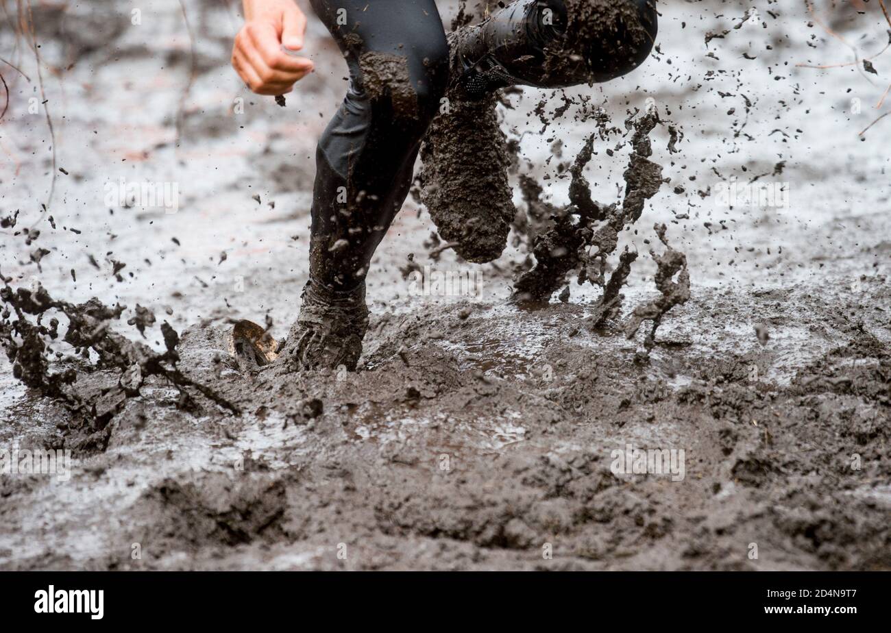 Mud race runner, man running in mud. Runners during extreme obstacle ...