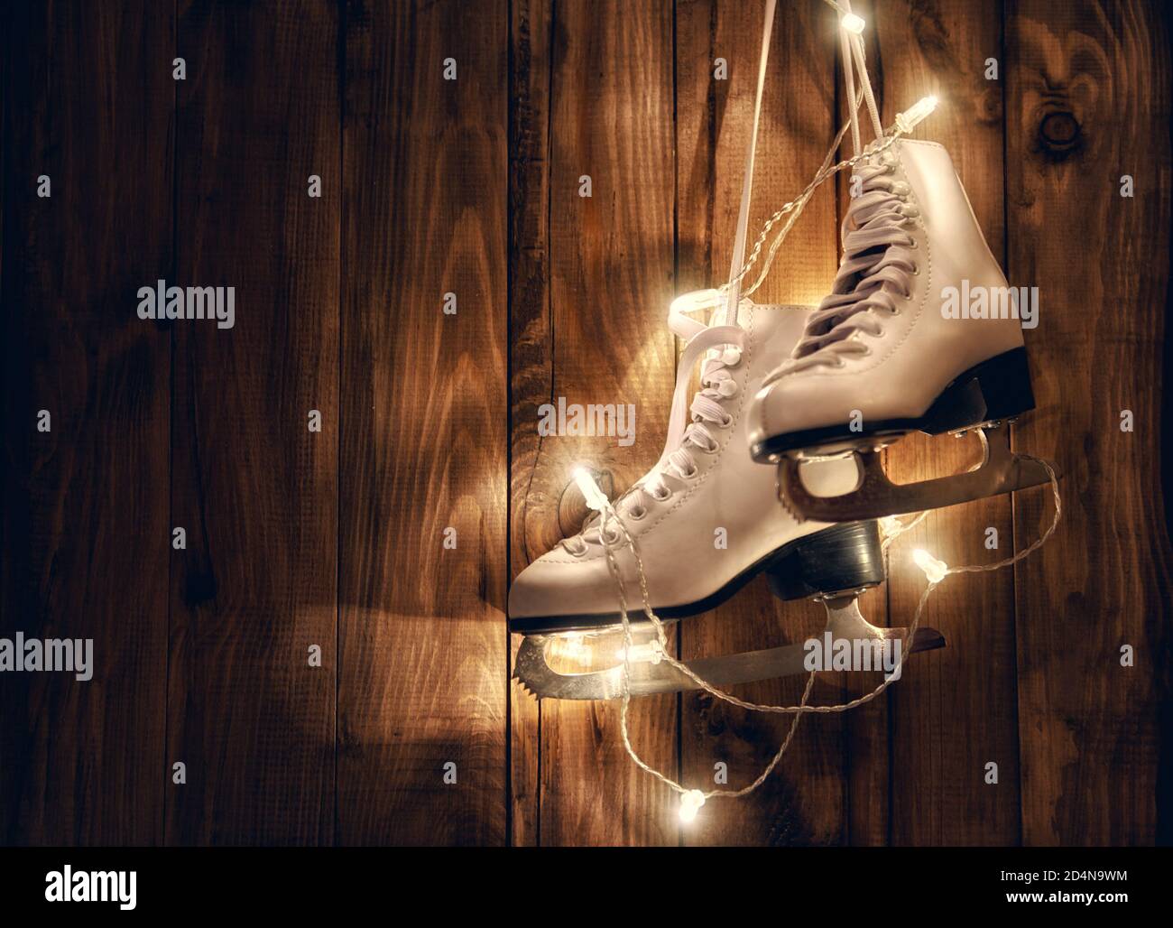 Figure skates and Christmas garland lights on old dark wooden rustic ...