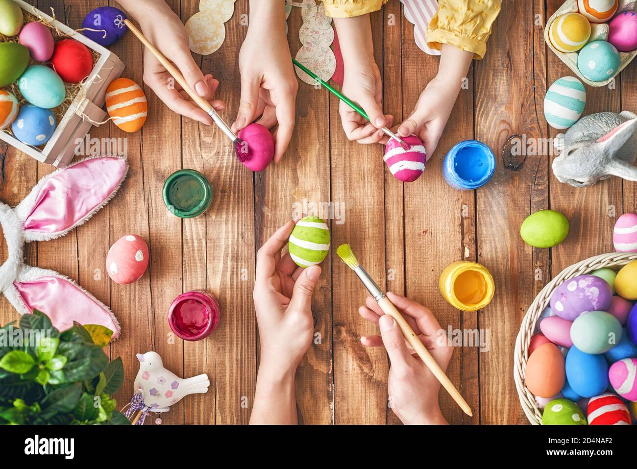 A mother, father and their child painting eggs. Happy family preparing ...