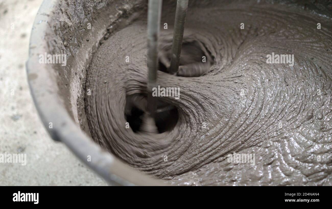 The solution in the bucket is mixed using a construction mixer. Mixing ...