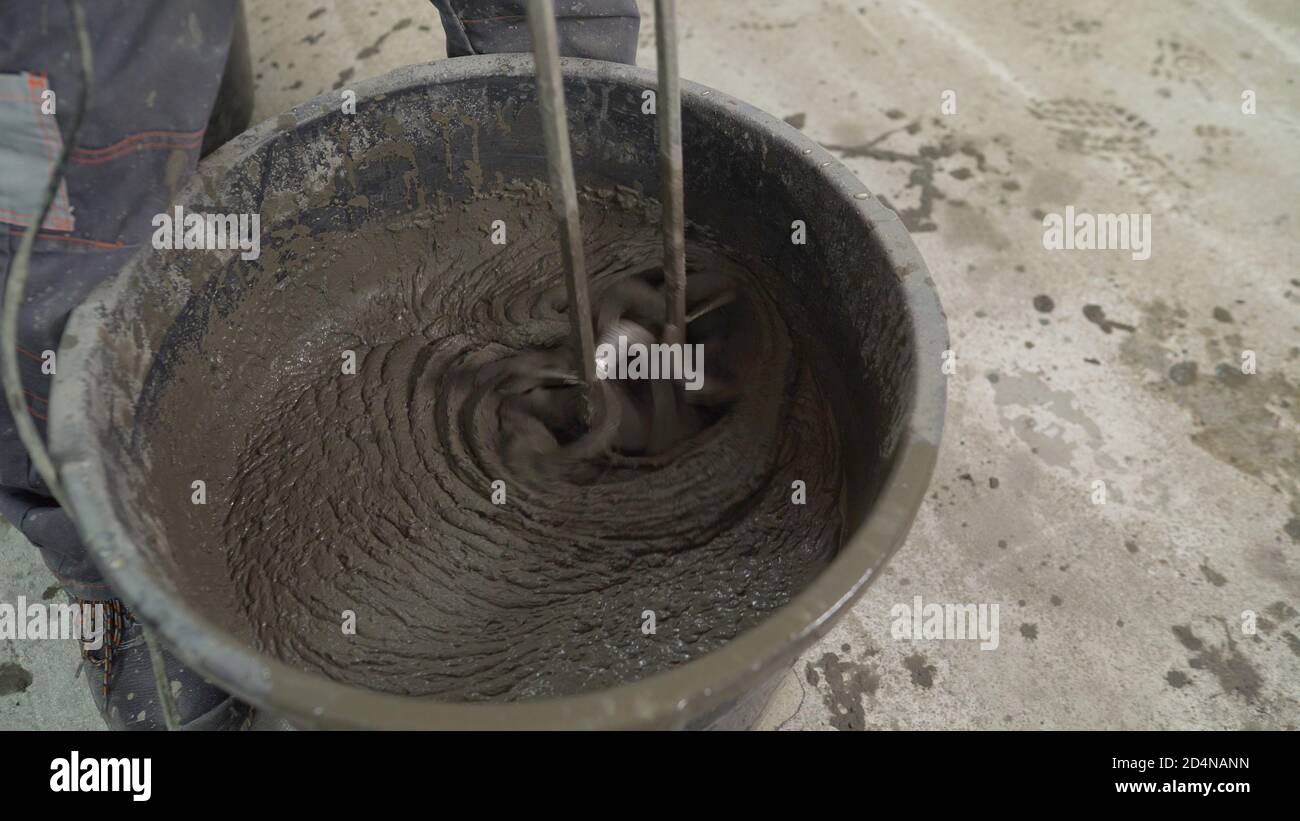 The solution in the bucket is mixed using a construction mixer. Mixing ...