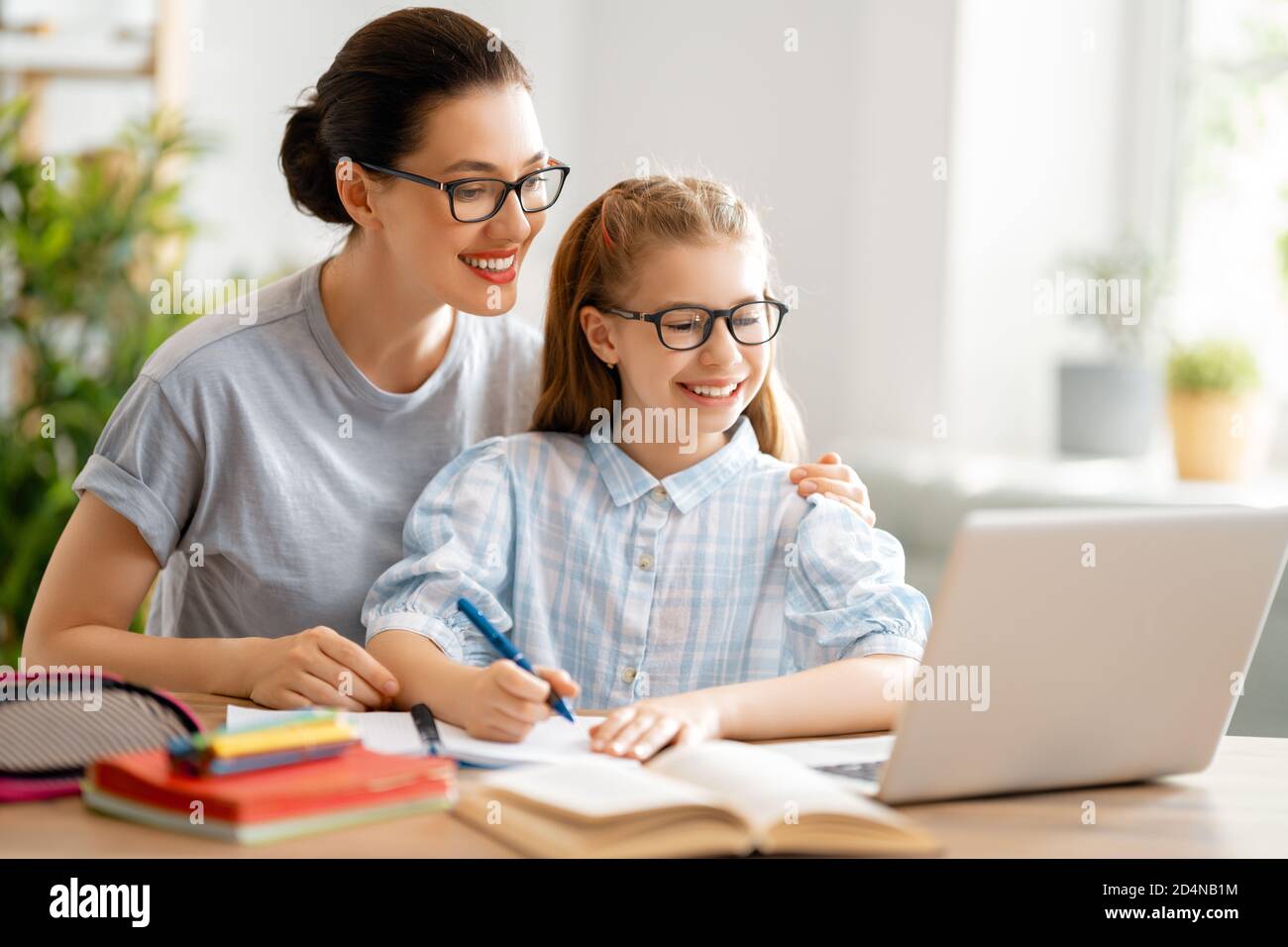 Back to school. Happy child and adult are sitting at desk. Girl doing ...