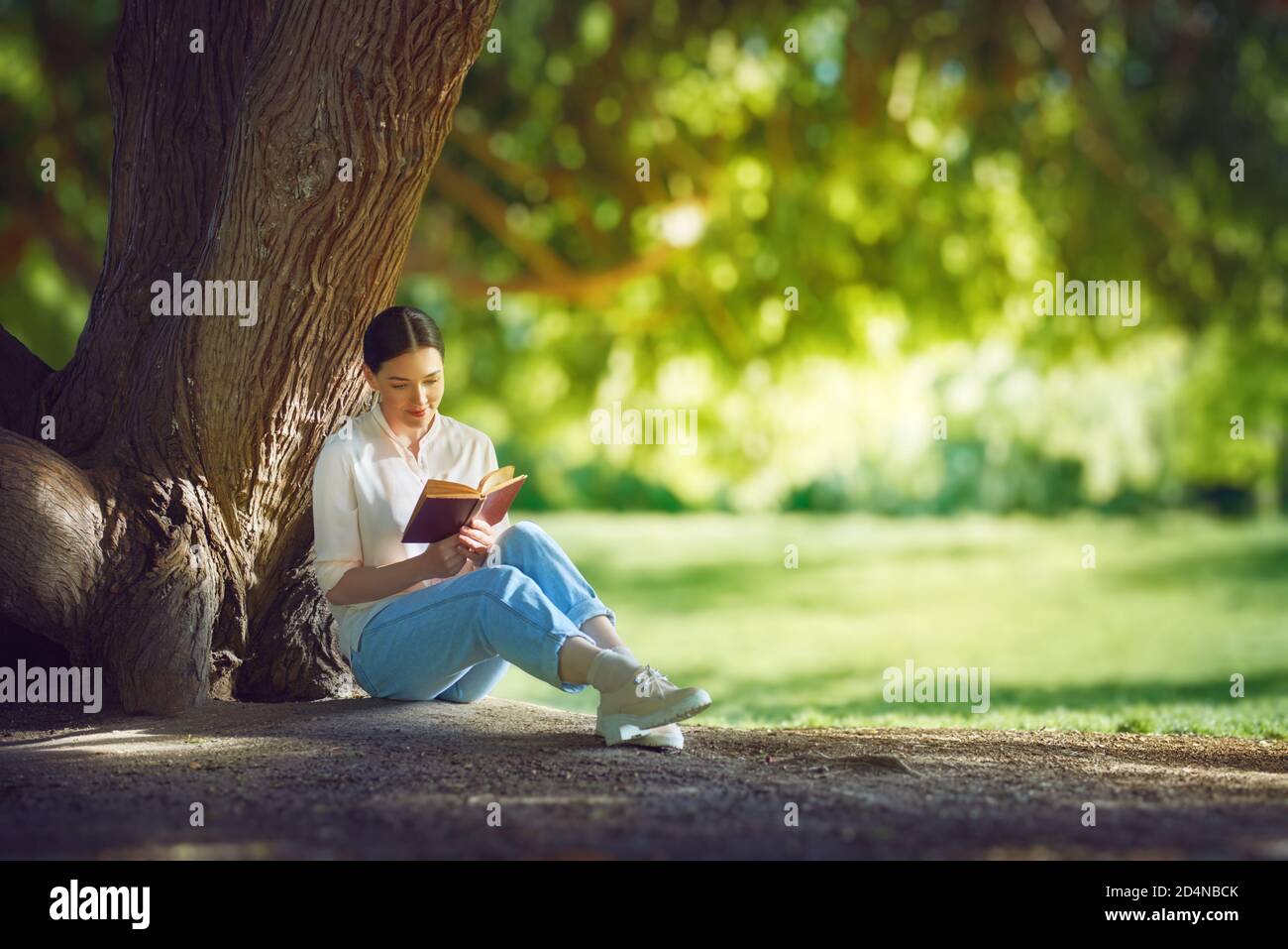 Little Girl Reading A Book Under A Tree