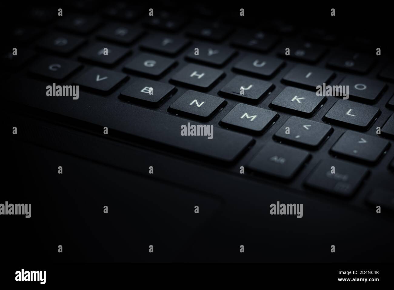 Closeup of black laptop QWERTY keyboard with light falling on keys ...
