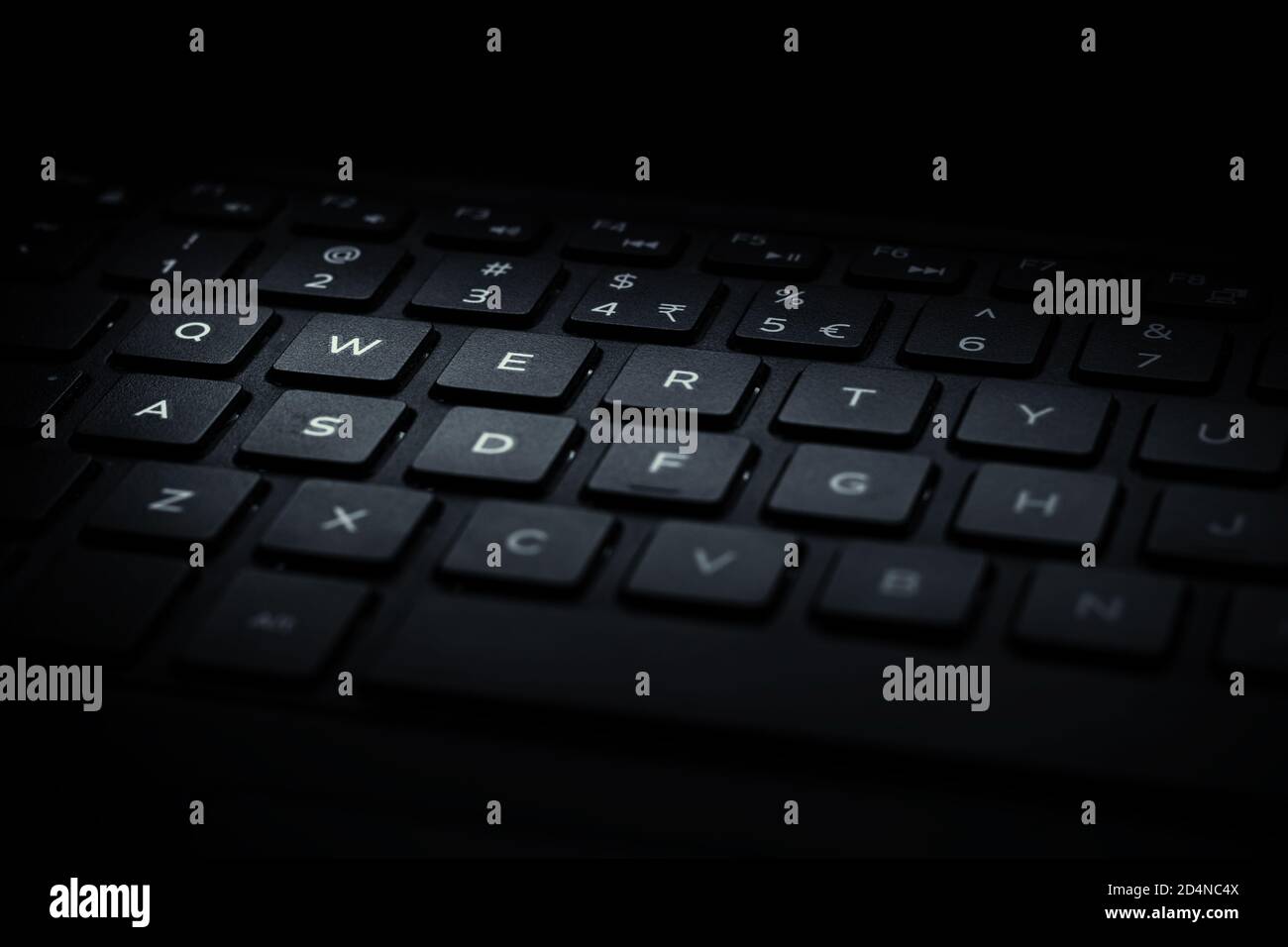 Closeup of black laptop QWERTY keyboard with light falling on keys ...