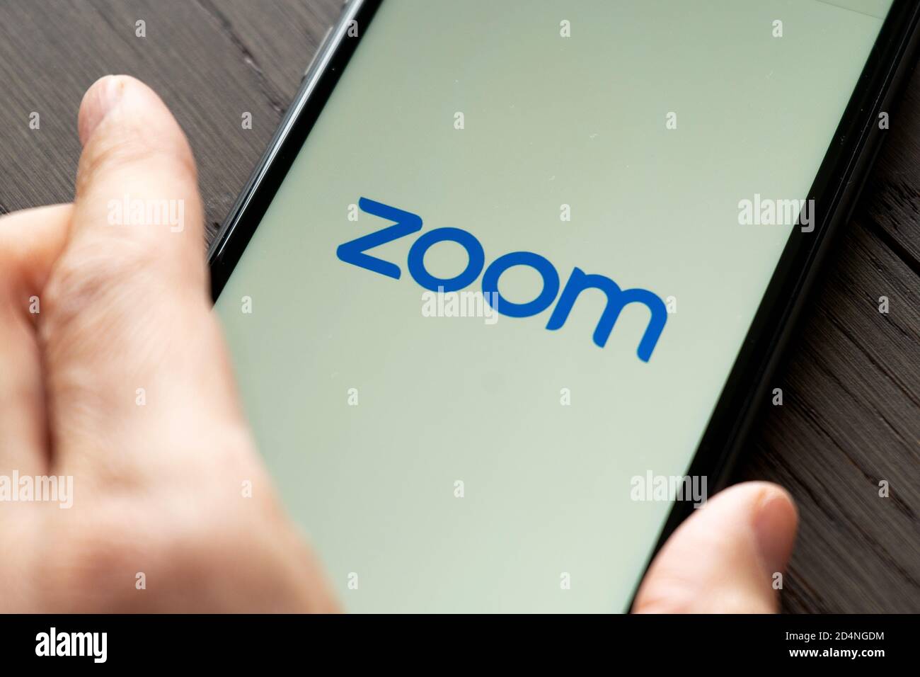 Phone with a hand showing Zoom Cloud Meetings app. Work and have ...