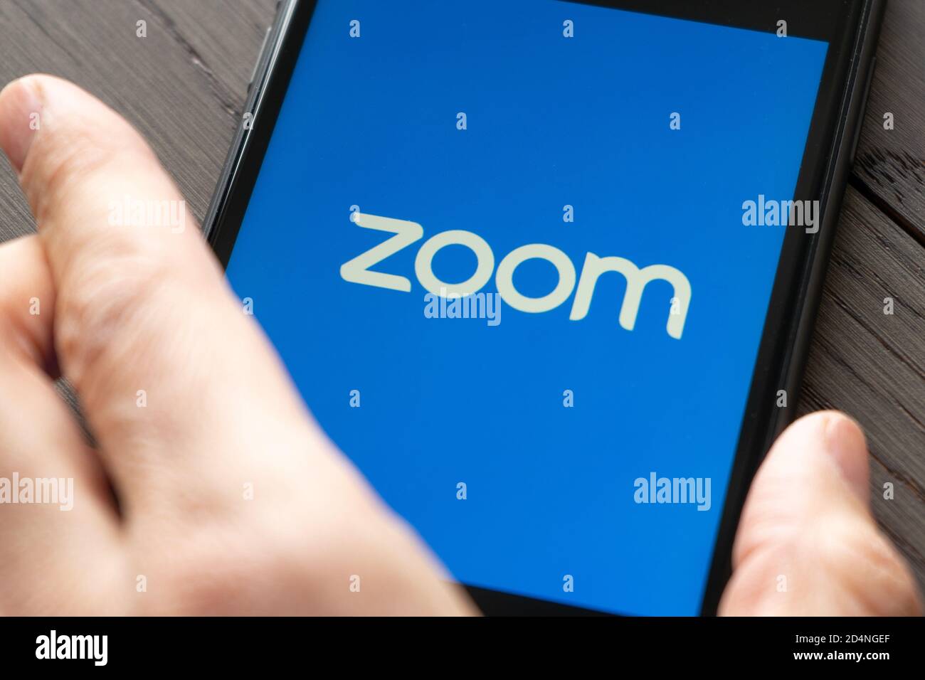 Phone with a hand showing Zoom Cloud Meetings app. Work and have ...
