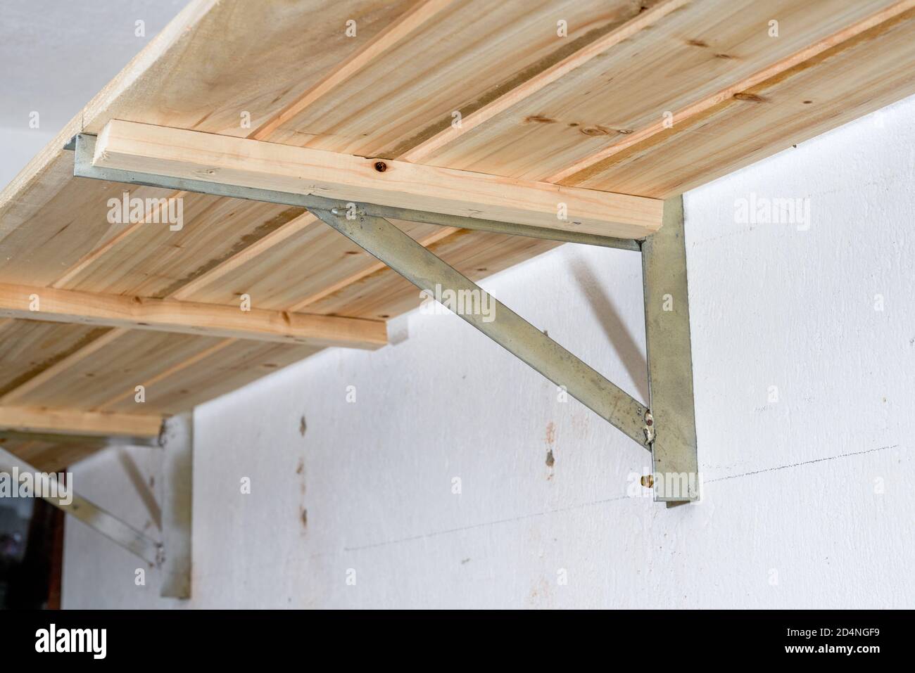 Close-up of a wooden shelf supported by a triangular iron frame on the ...