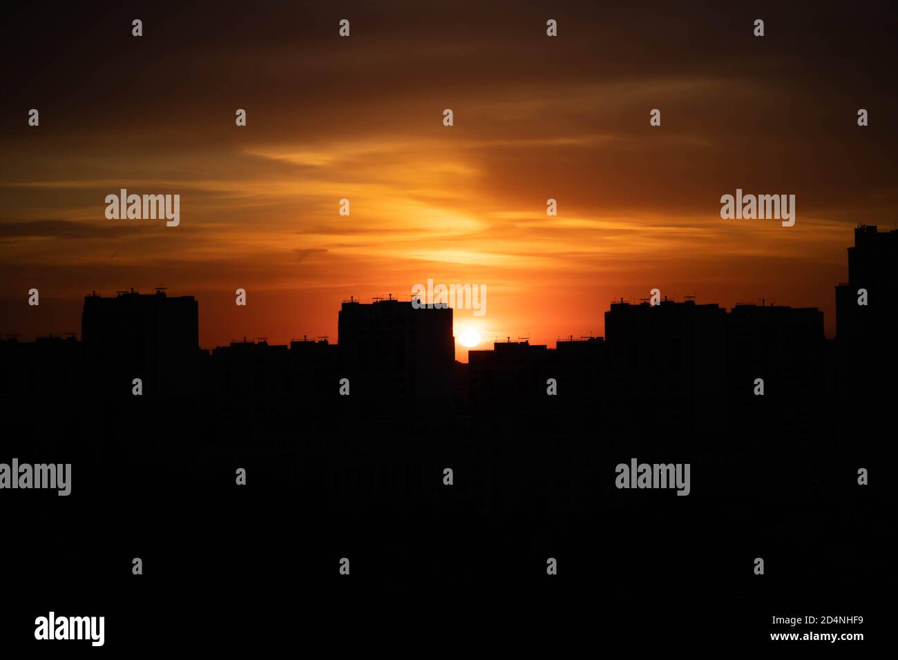 Big city in the rays of the sunset. High-rise black houses and red ...